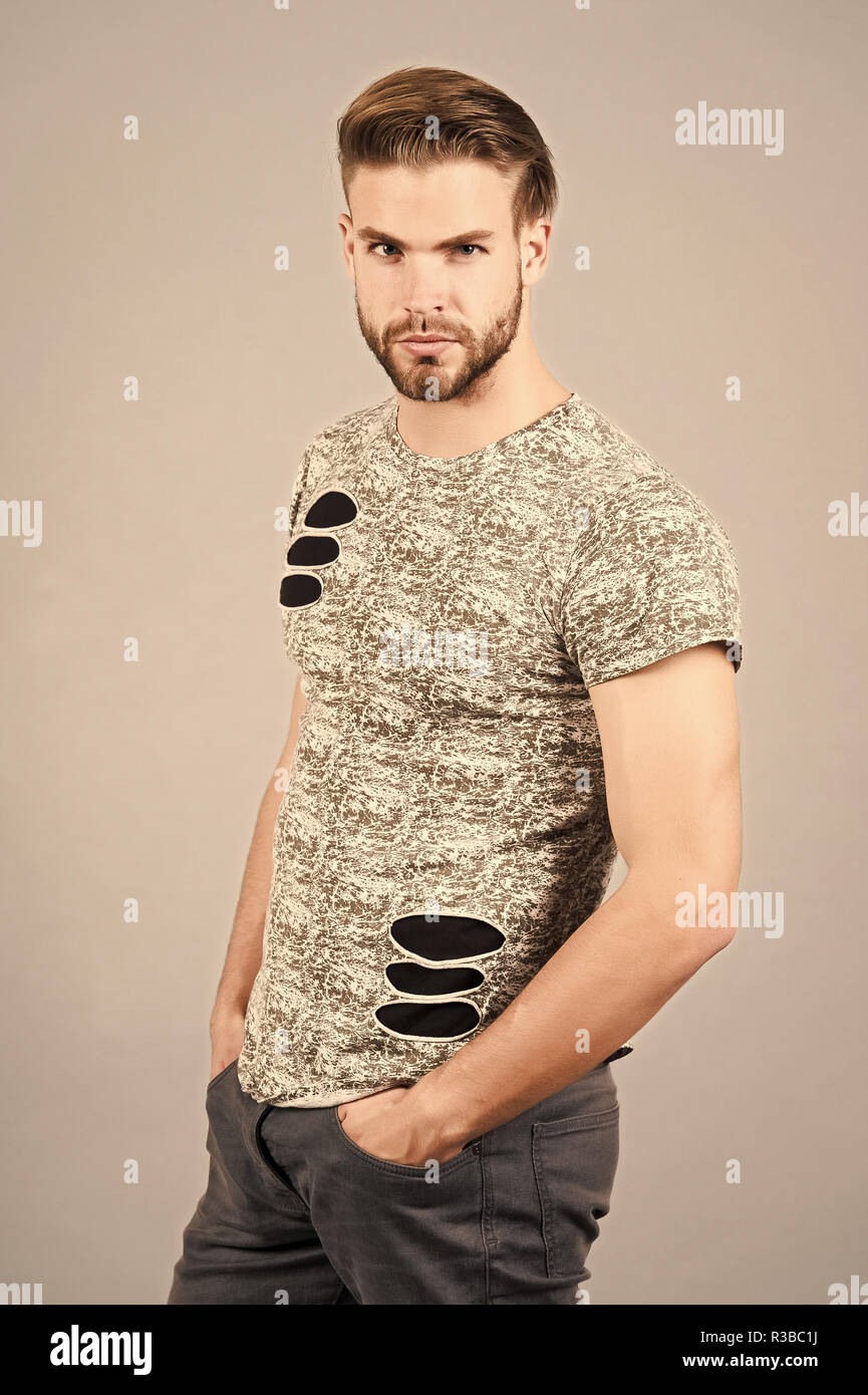Macho with beard in tshirt pose with hands in jeans pockets on grey ...