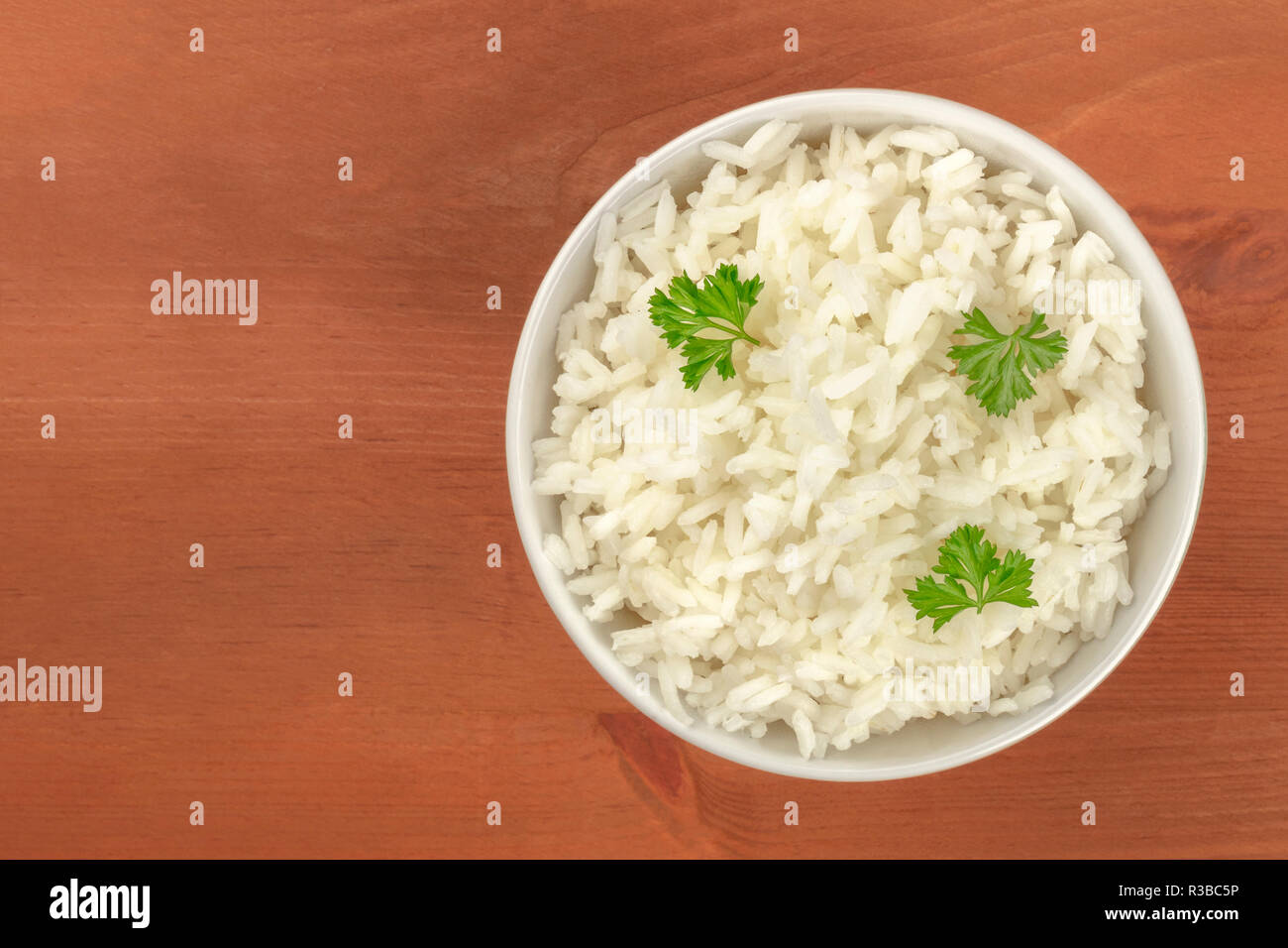 A bowl of cooked white long grain Basmati rice, garnished with parsley ...