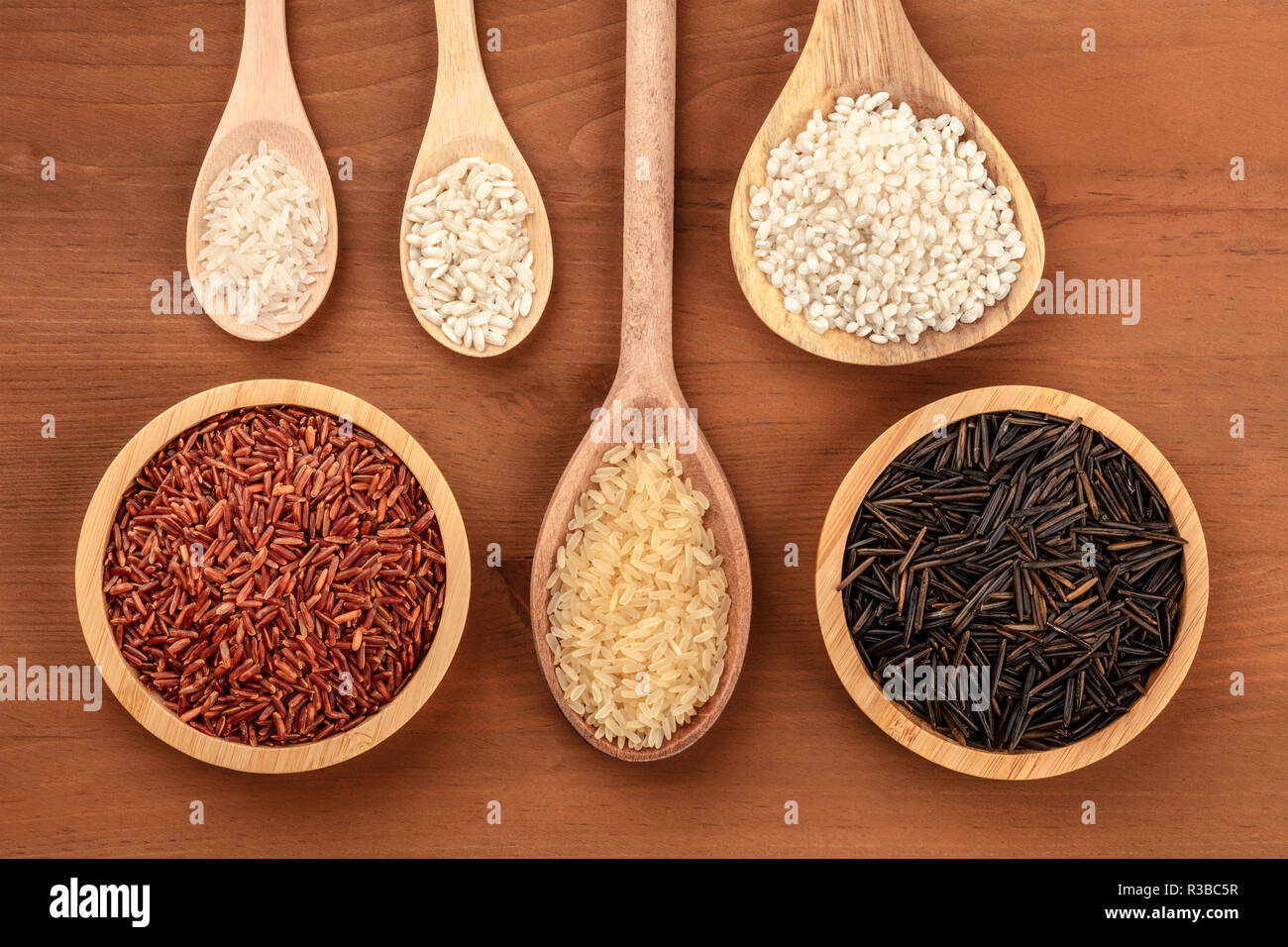 A collection of various rice types, shot from the top on a dark rustic ...