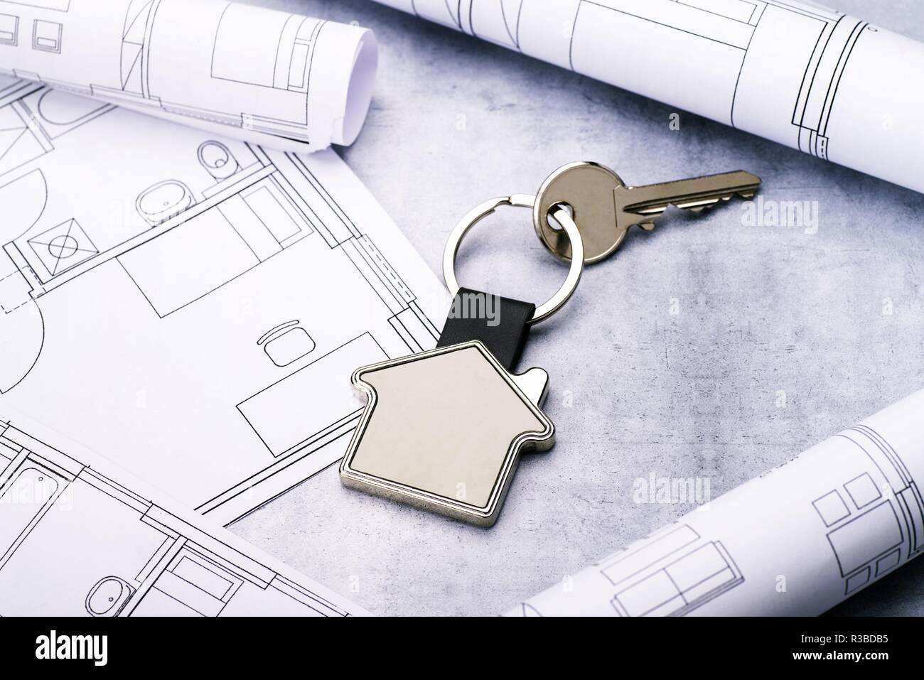Key with house as key fob and blueprints on a concrete background ...