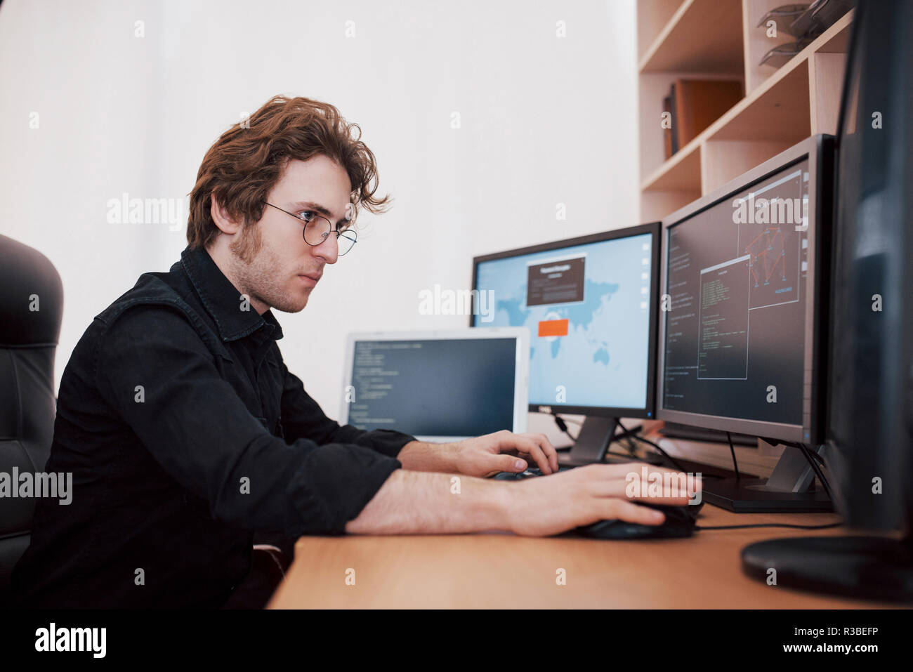 Male programmer working on desktop computer with many monitors at ...