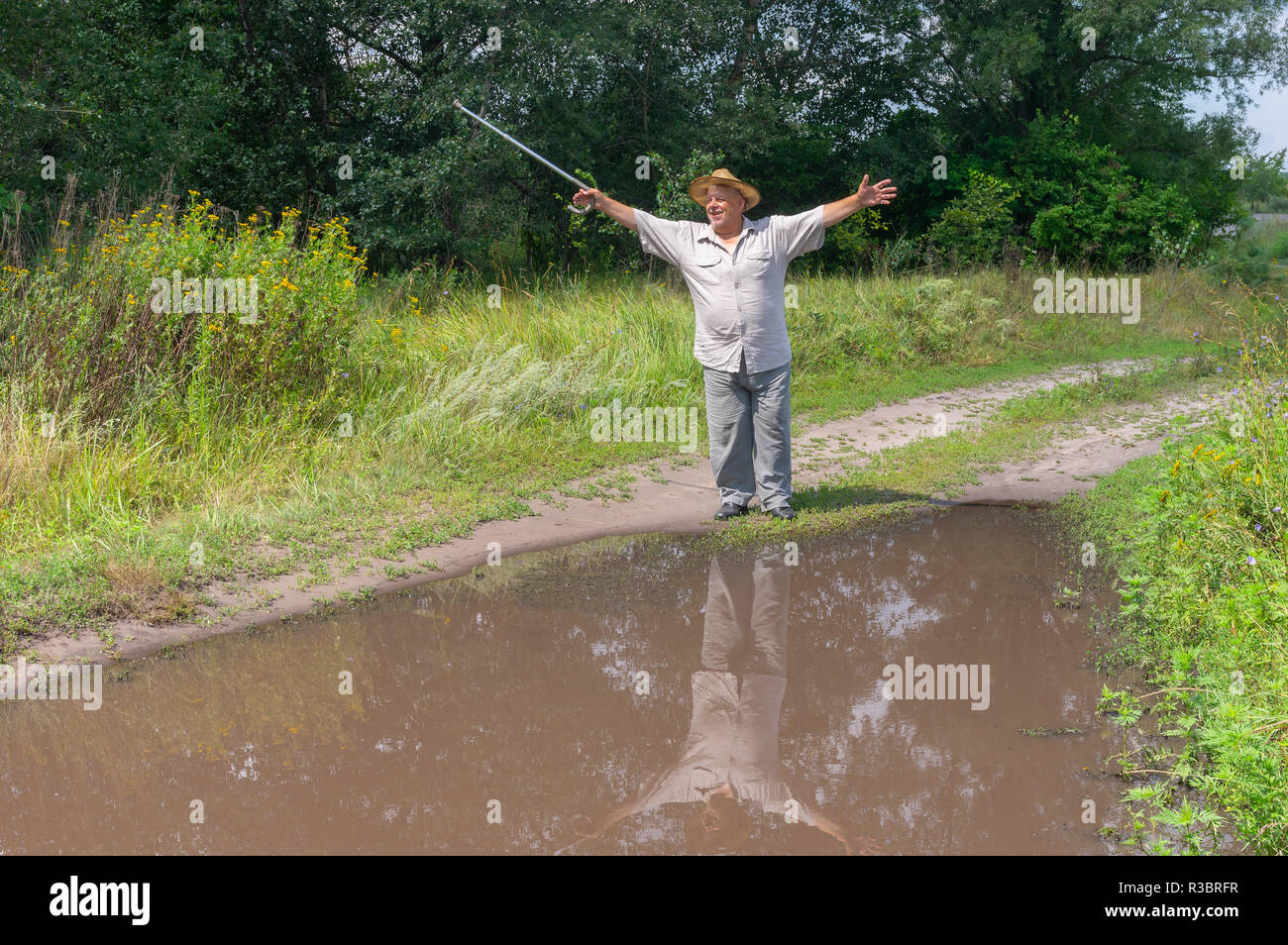 Senior man shows how big is a puddle on the country road Stock Photo ...
