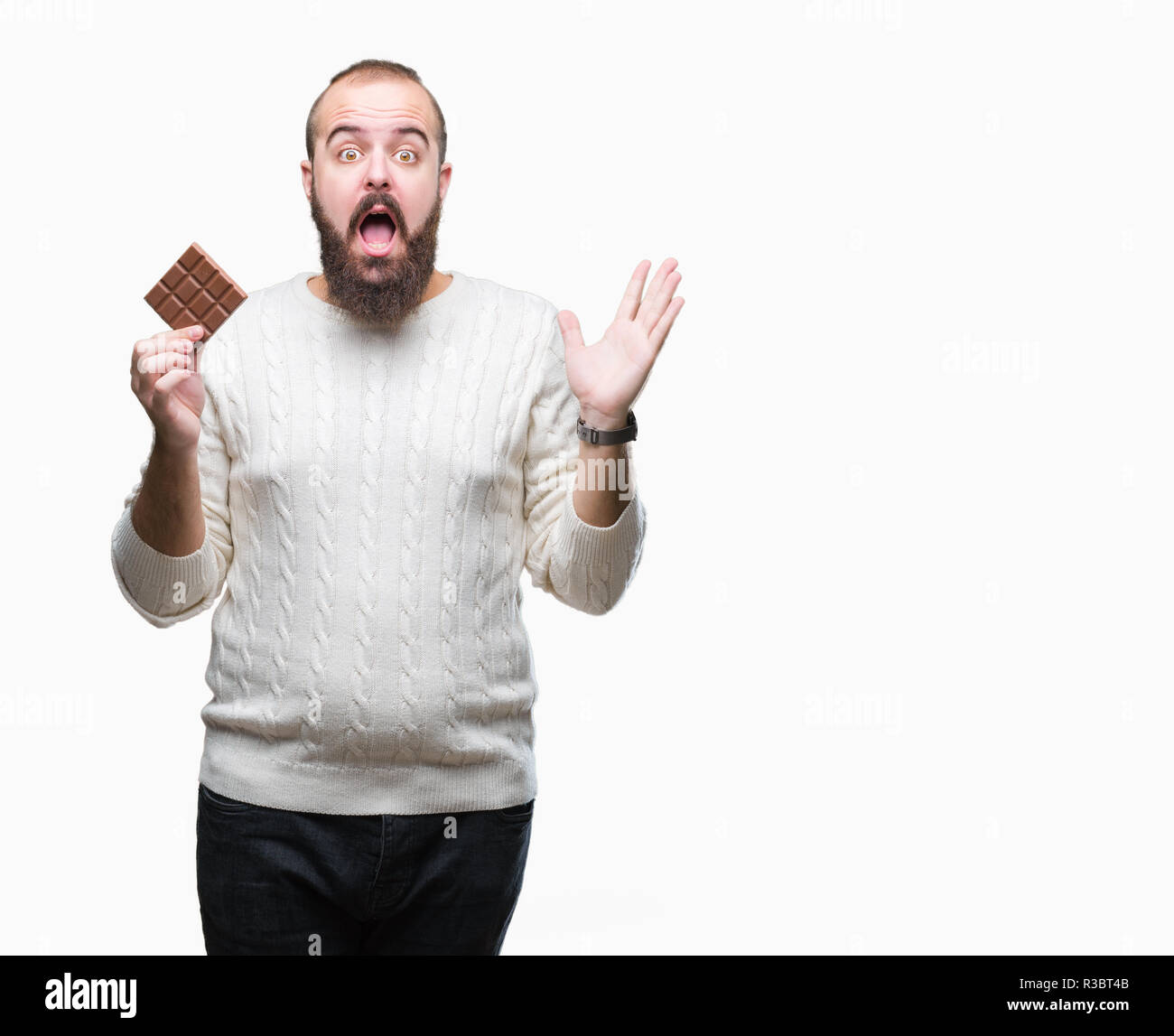 Young hipster man eating chocolate bar over isolated background very ...