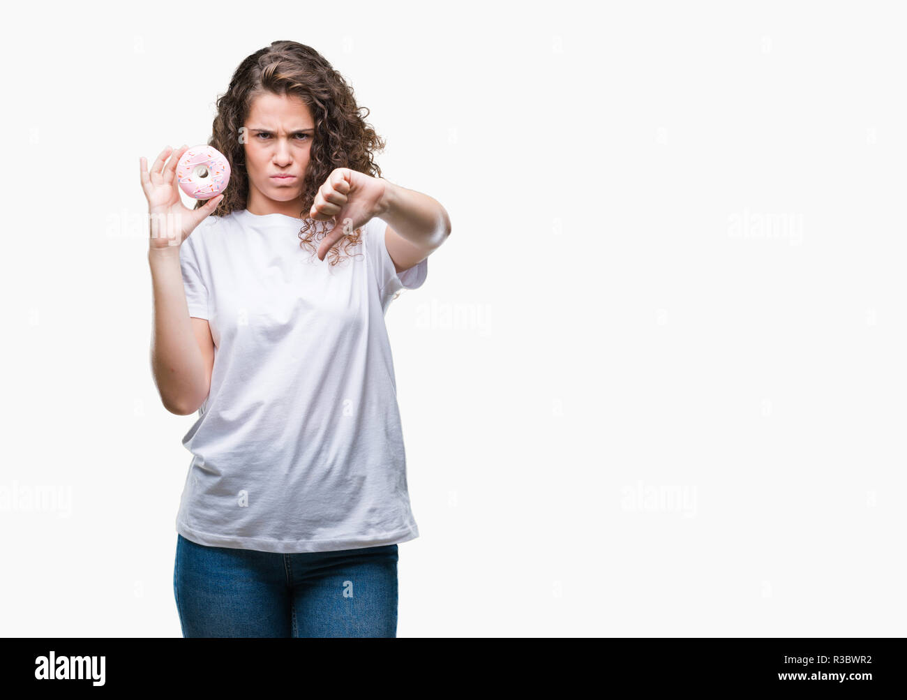 Young brunette girl eating donut over isolated background with angry ...