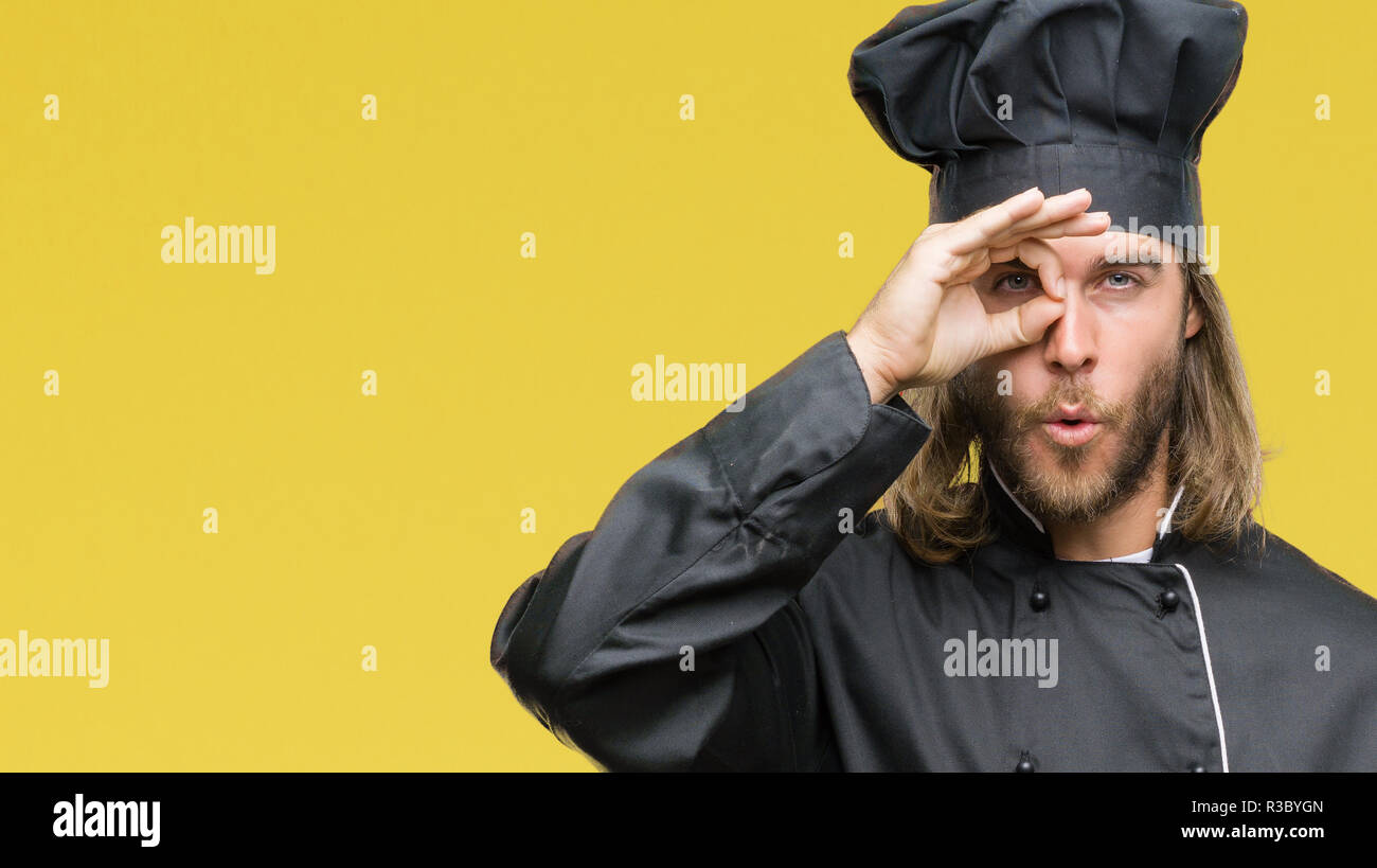 Young handsome cook man with long hair over isolated background doing ...