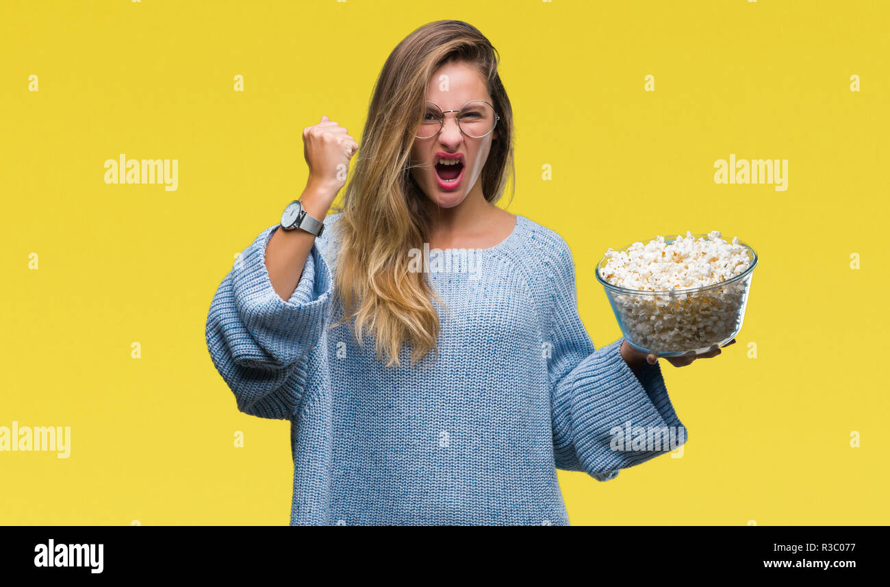 Young beautiful blonde woman eating popcorn over isolated background ...