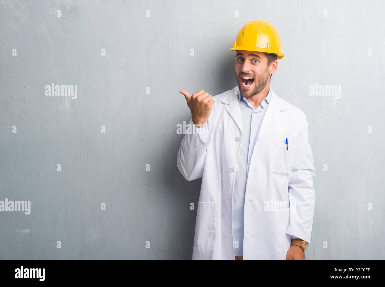 Handsome young engineer man over grey grunge wall wearing safety helmet ...