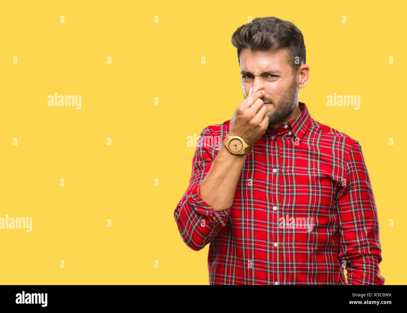 Young handsome man over isolated background smelling something stinky ...