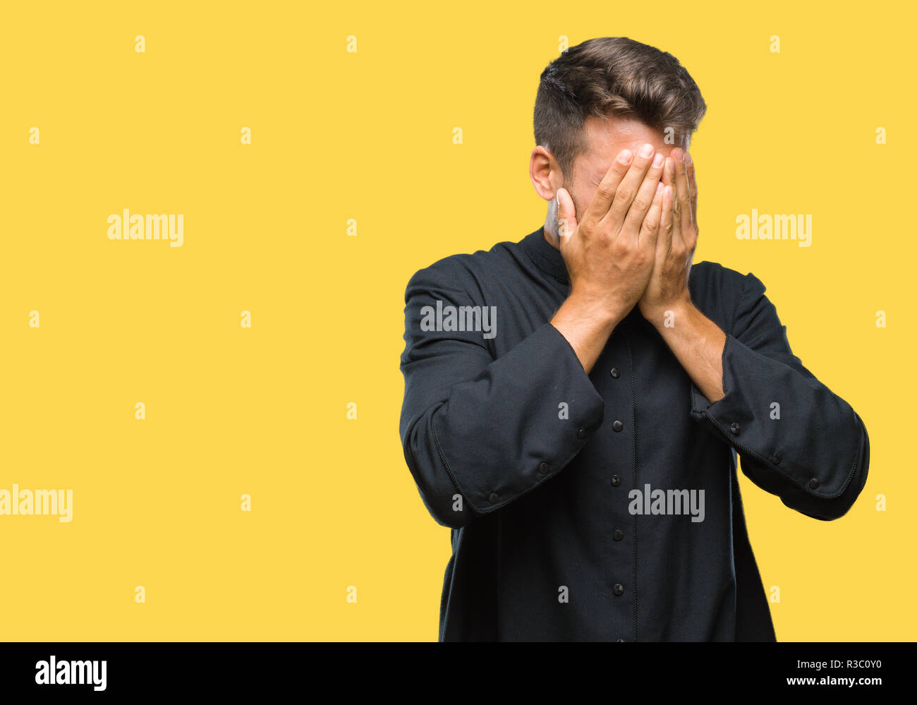 Young catholic christian priest man over isolated background with sad ...