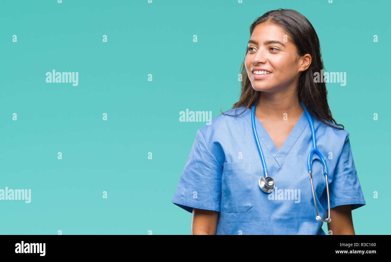 Young arab doctor surgeon woman over isolated background looking away ...