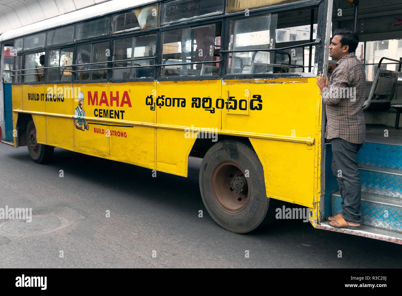 One man footboarding on an empty bus at a bus station in Hyderabad ...