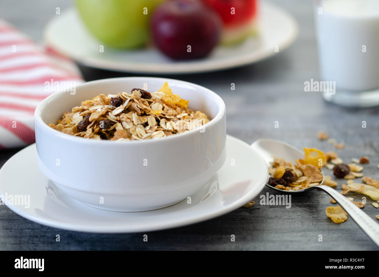 Granola cereal flakes with dried fruit, nuts and honey in a white bowl ...