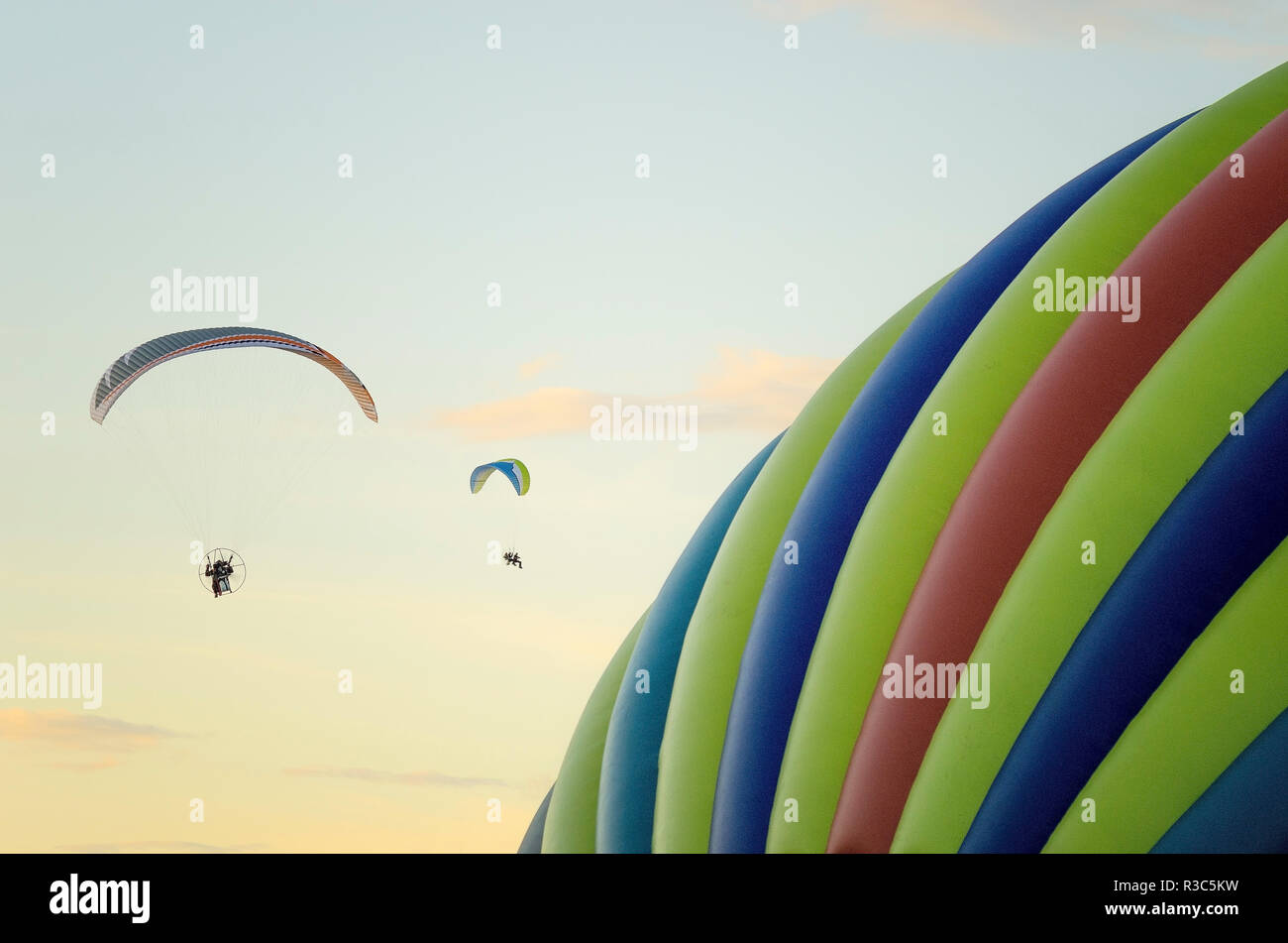 Two paragliders flying over a large colorful inflated stage Stock Photo ...