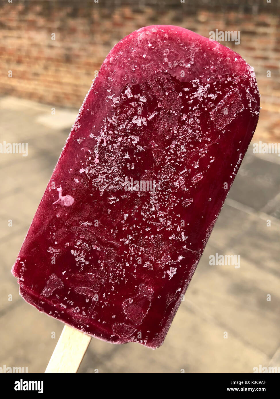 Frosty ice texture on a red ice lolly with an industrial background of ...