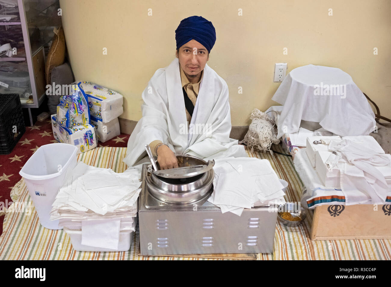 An observant Sikh man sitting at the rear of the temple preparing to ...