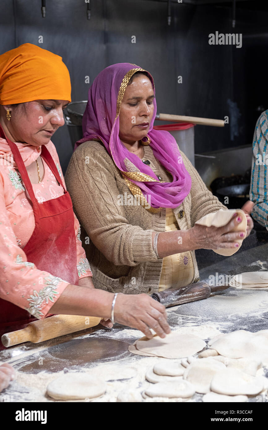 Two Sikh women make roti for a langar, a free communal lunchroom in a ...