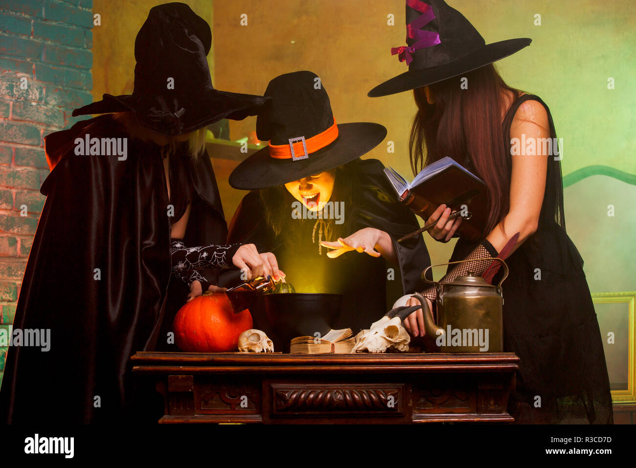 Photo of three witches with book of boiling potions in cauldron at dark ...