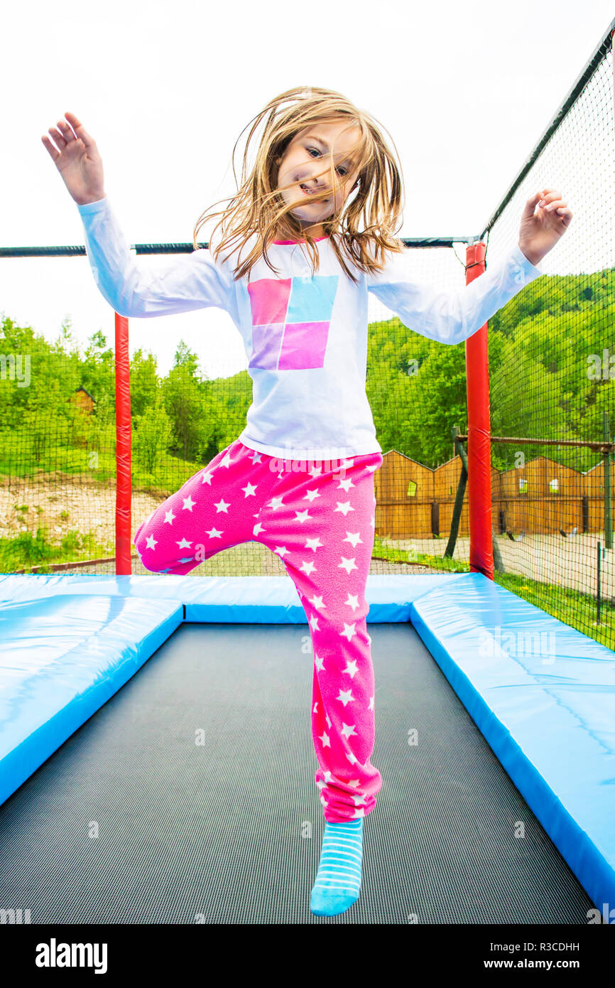 Happy girl jumping high on a trampoline on a sunny day outdoors Stock ...