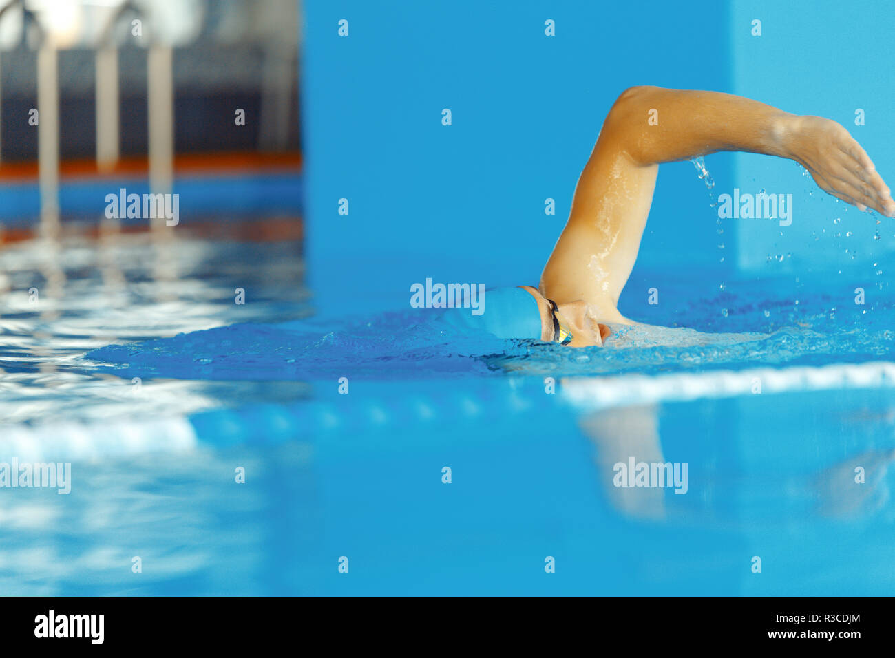 Image of young athlete man in blue cap swimming in pool during workout ...