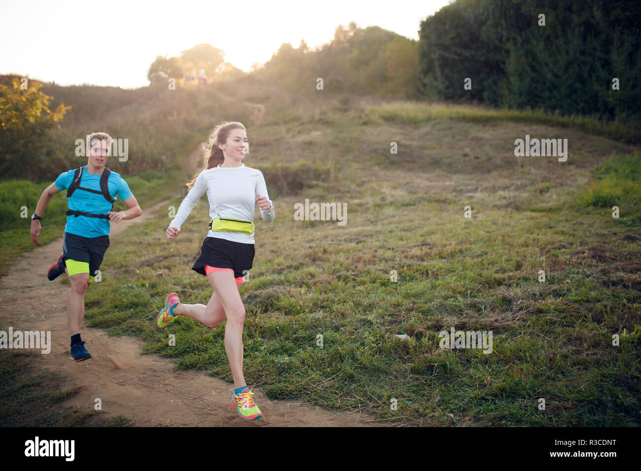 Image of athlete woman and man running through park on summer morning ...