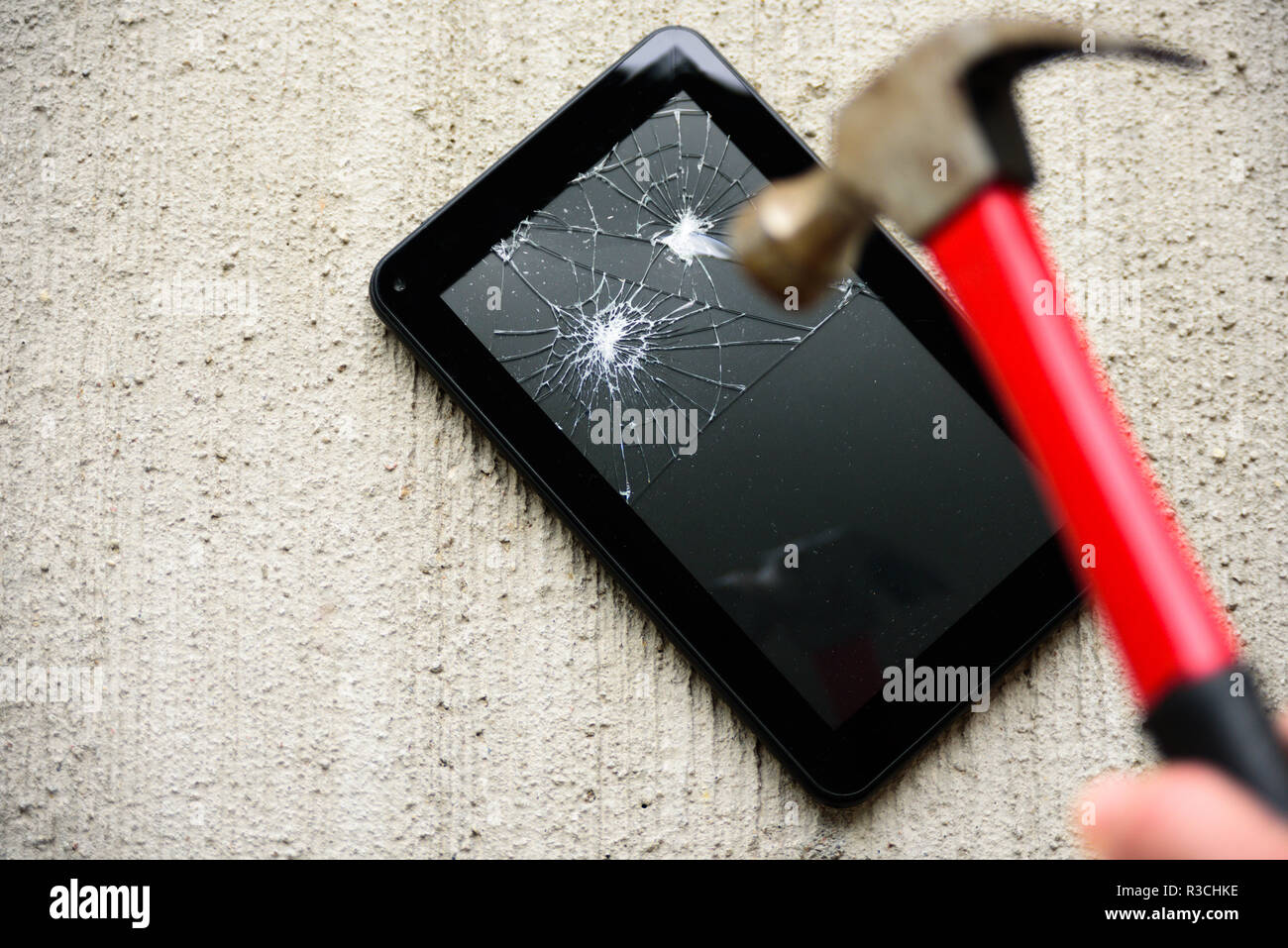 Hammering screen of tablet by old rusty hammer on concrete background ...