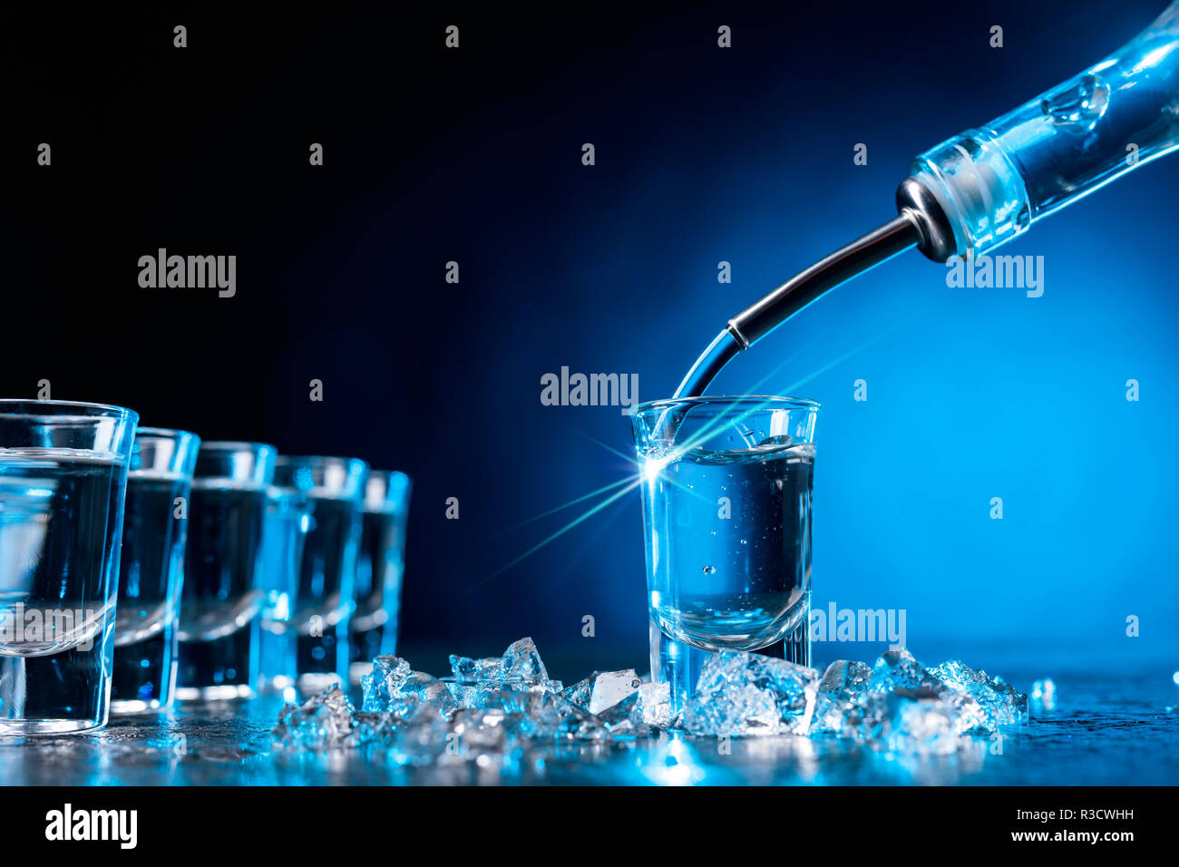 Vodka poured into a glass lit with blue backlight. Copy space.Chilled ...