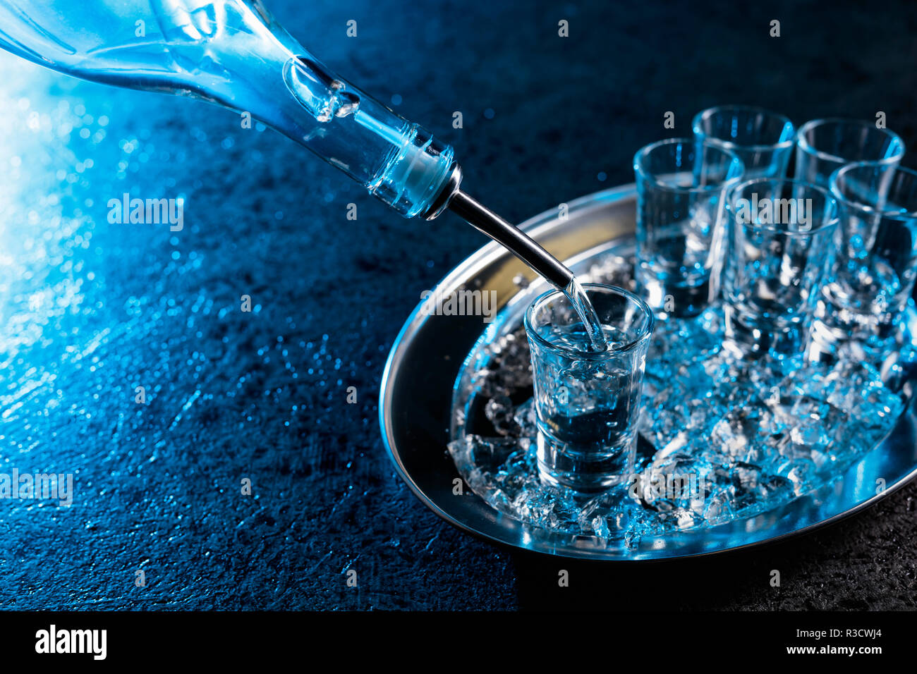 Vodka poured into a glass lit with blue backlight.Chilled vodka with ...