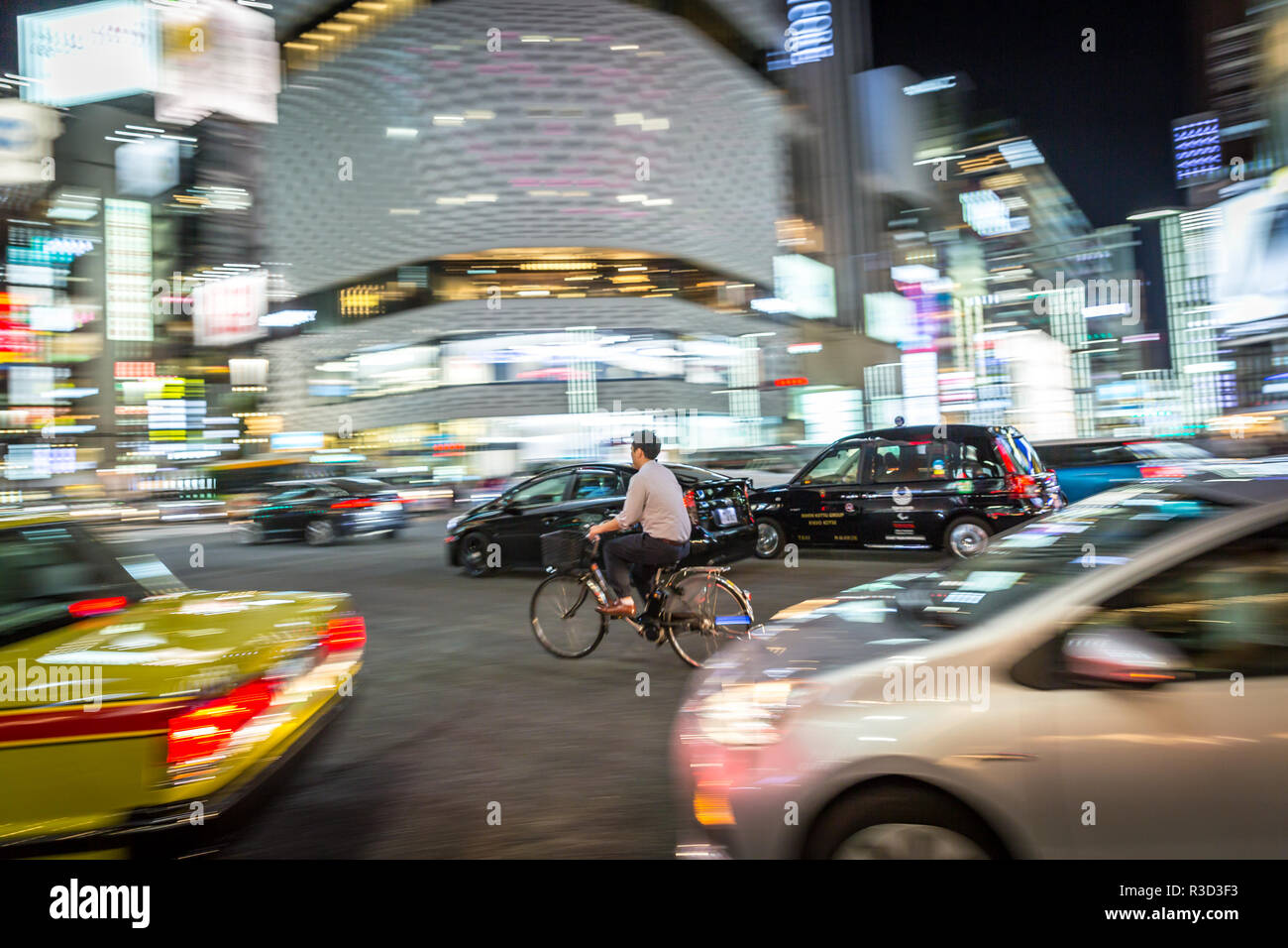 Tokyo, Japan - A local riding a bicycle through the traffic in downtown ...