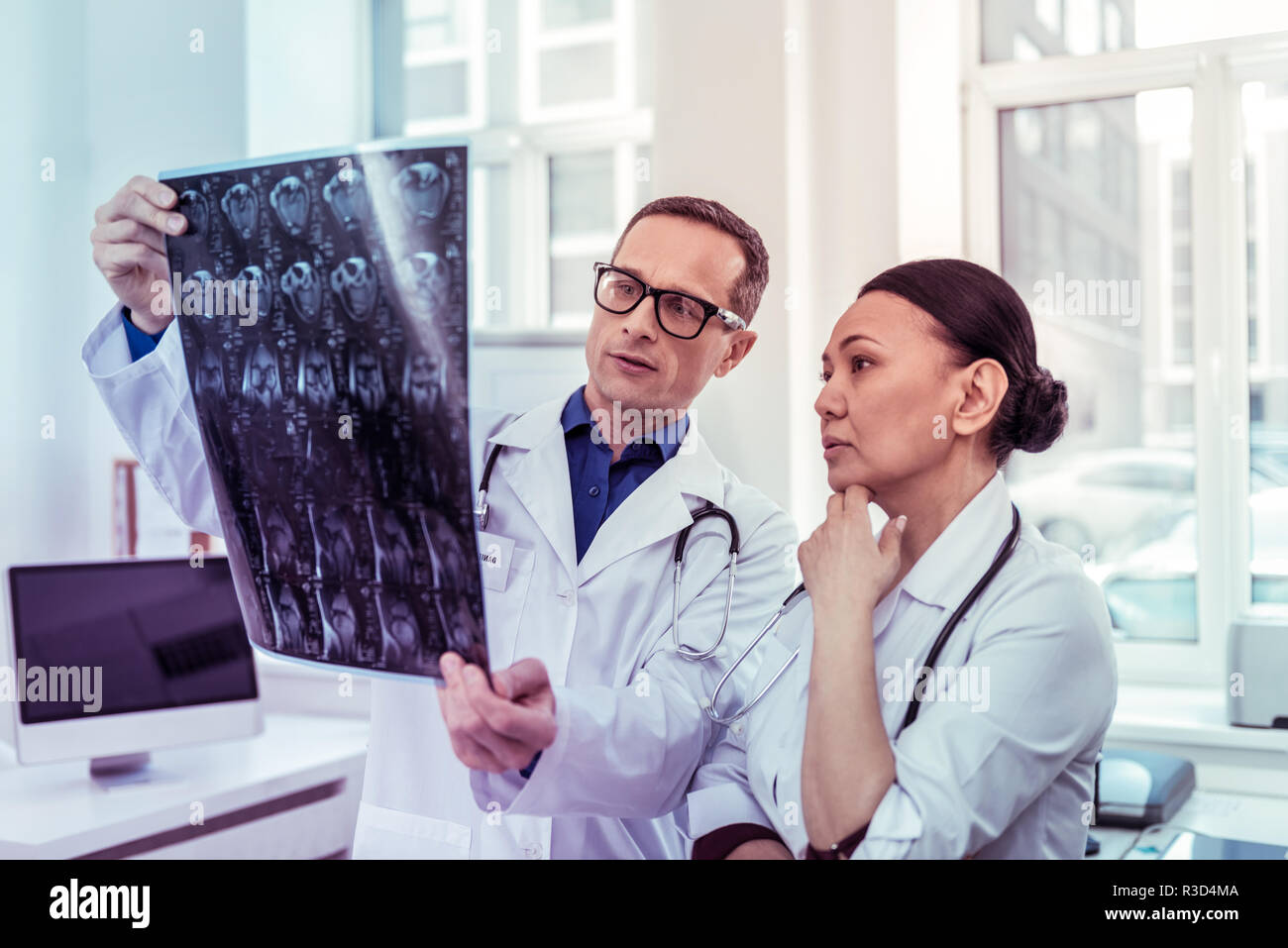 Collective work. Cheerful lab assistant raising hands while holding X ...