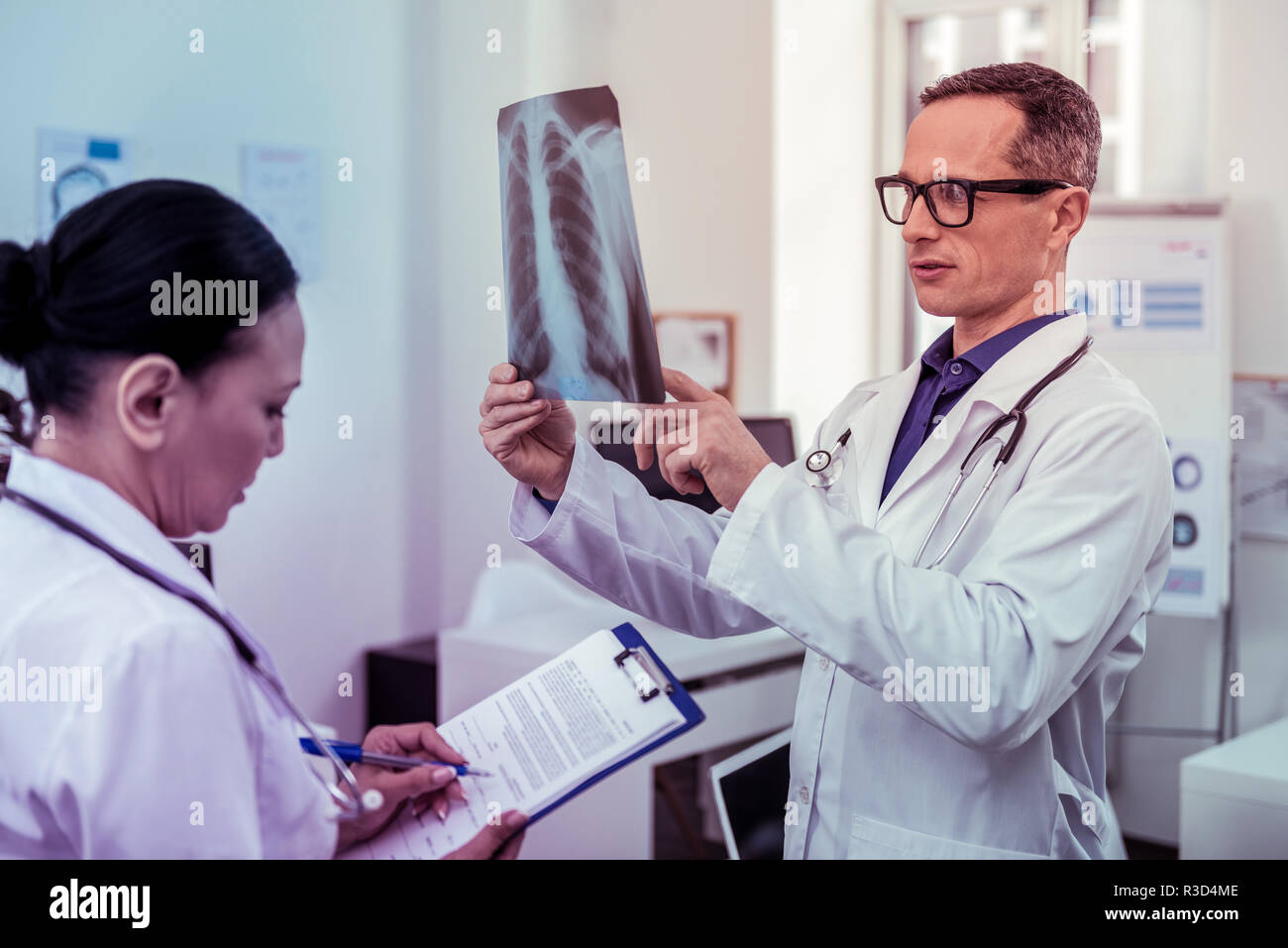 Making notes. Attentive young man checking results, staring at roentgen ...