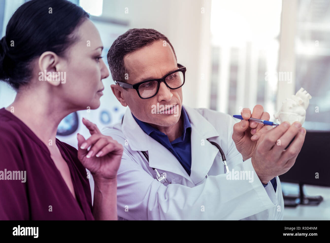 I am serious. Concentrated man pointing at model of heart while giving ...