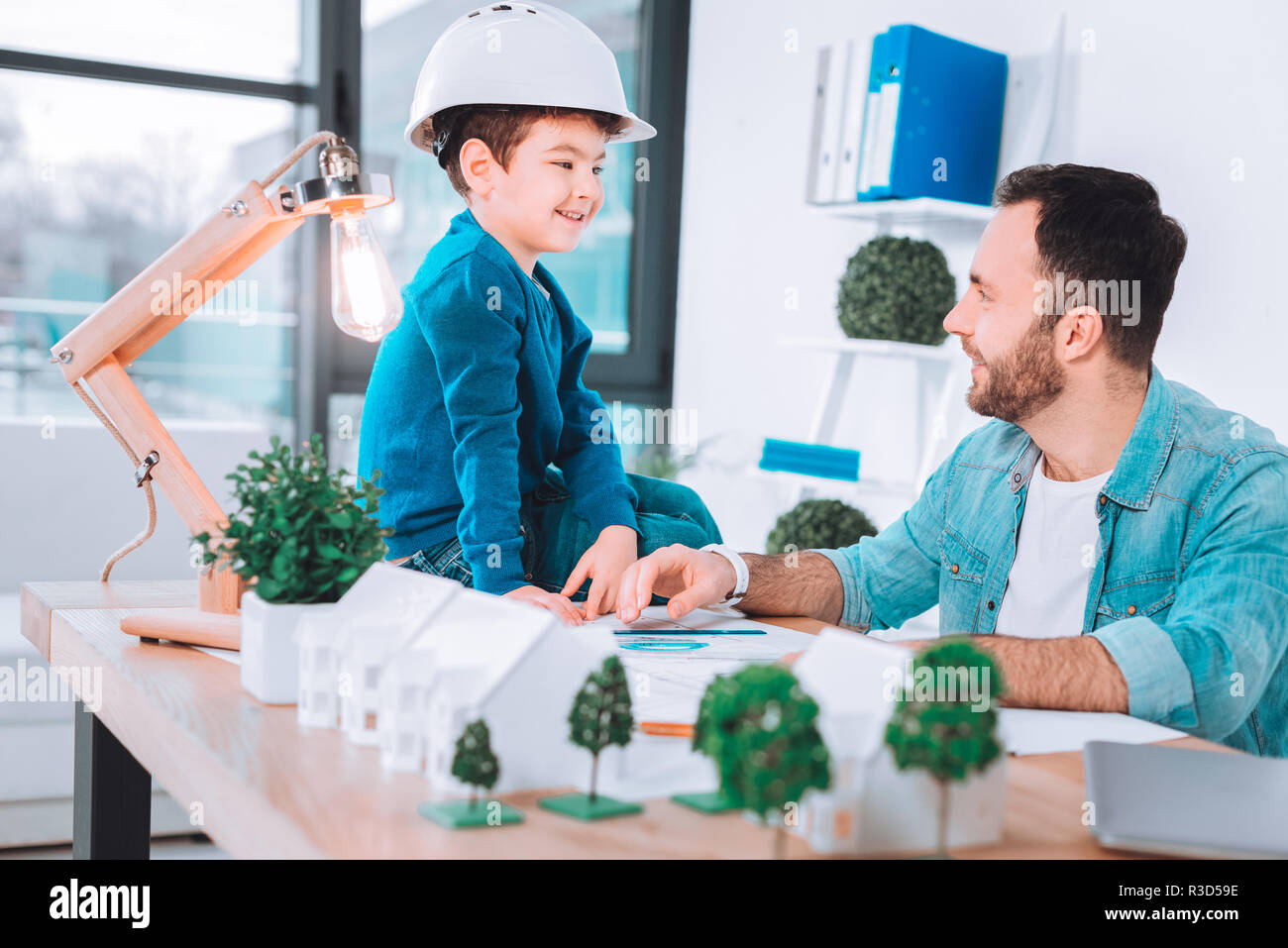 Team work. High-spirited energetic father and a son sitting in an ...