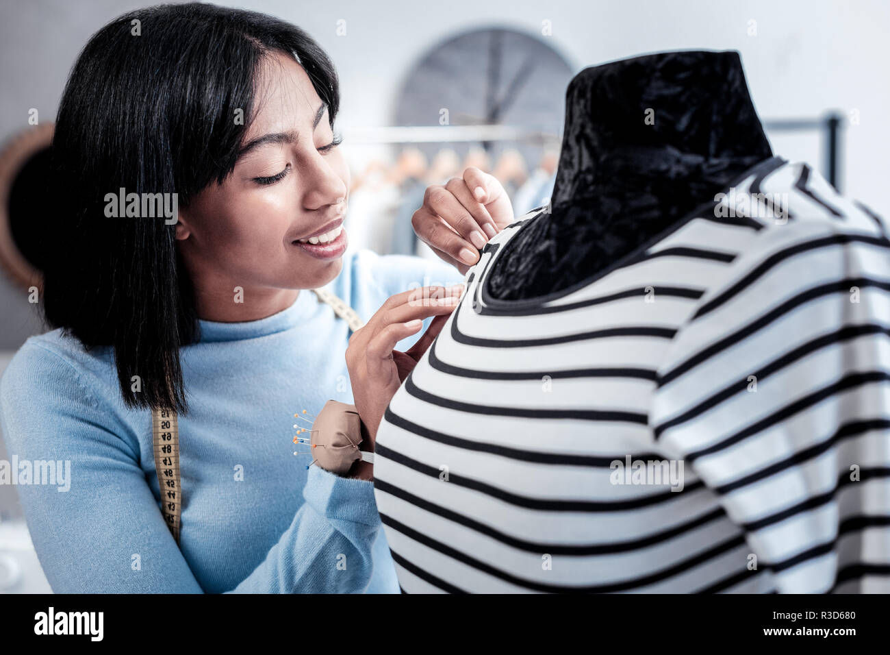 Careful work. Cheerful positive woman smiling while focusing on her ...