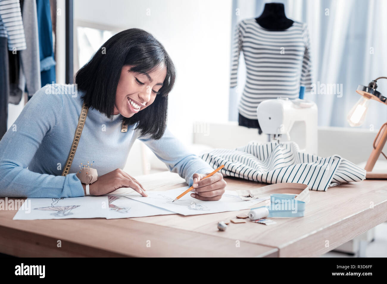 Fashion design. Positive smart designer drawing sketches while being at ...