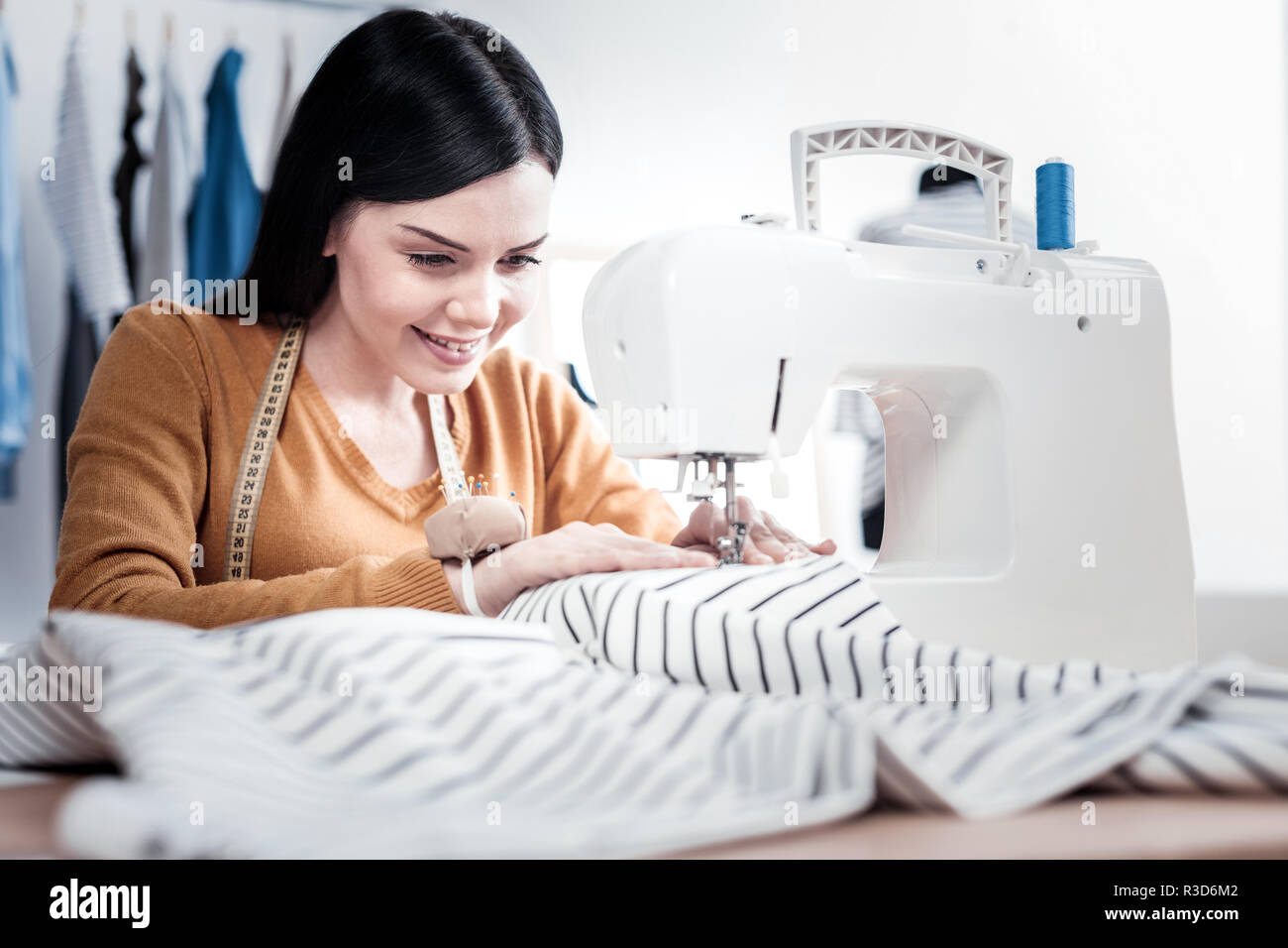 Designers studio. Happy skilled tailor using professional equipment ...