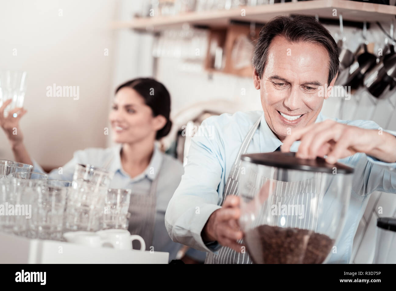 Professional equipment. Positive skilled man using coffee machine while ...