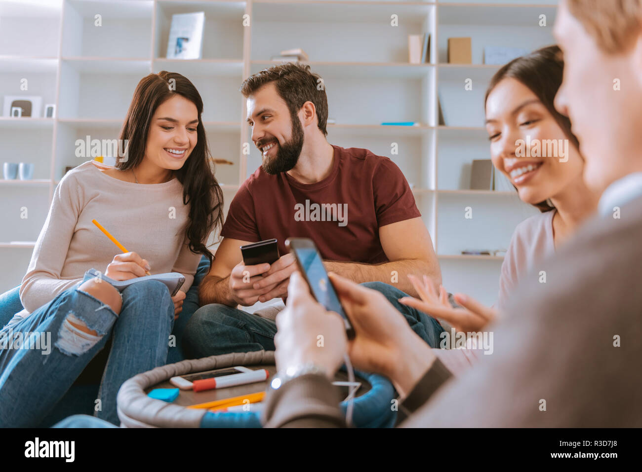 Technology and fun. Energetic four friends using gadgets and talking ...