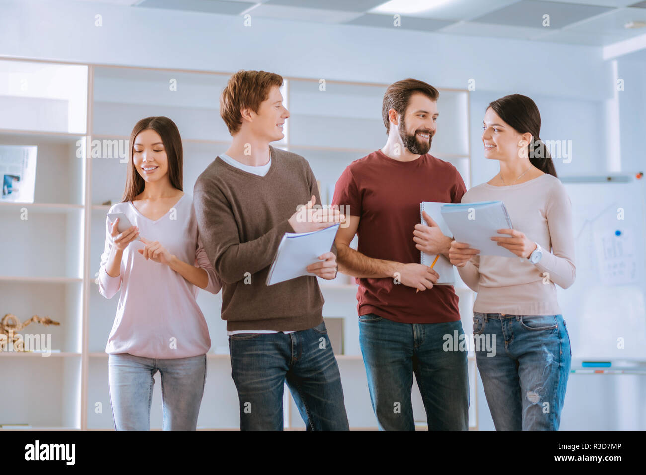 Vivid communication. Low angle of glad four colleagues standing and ...