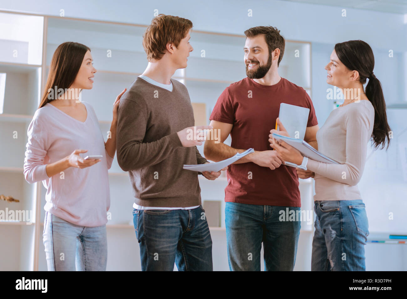 Team discussion. Low angle of optimistic four colleagues staying and ...