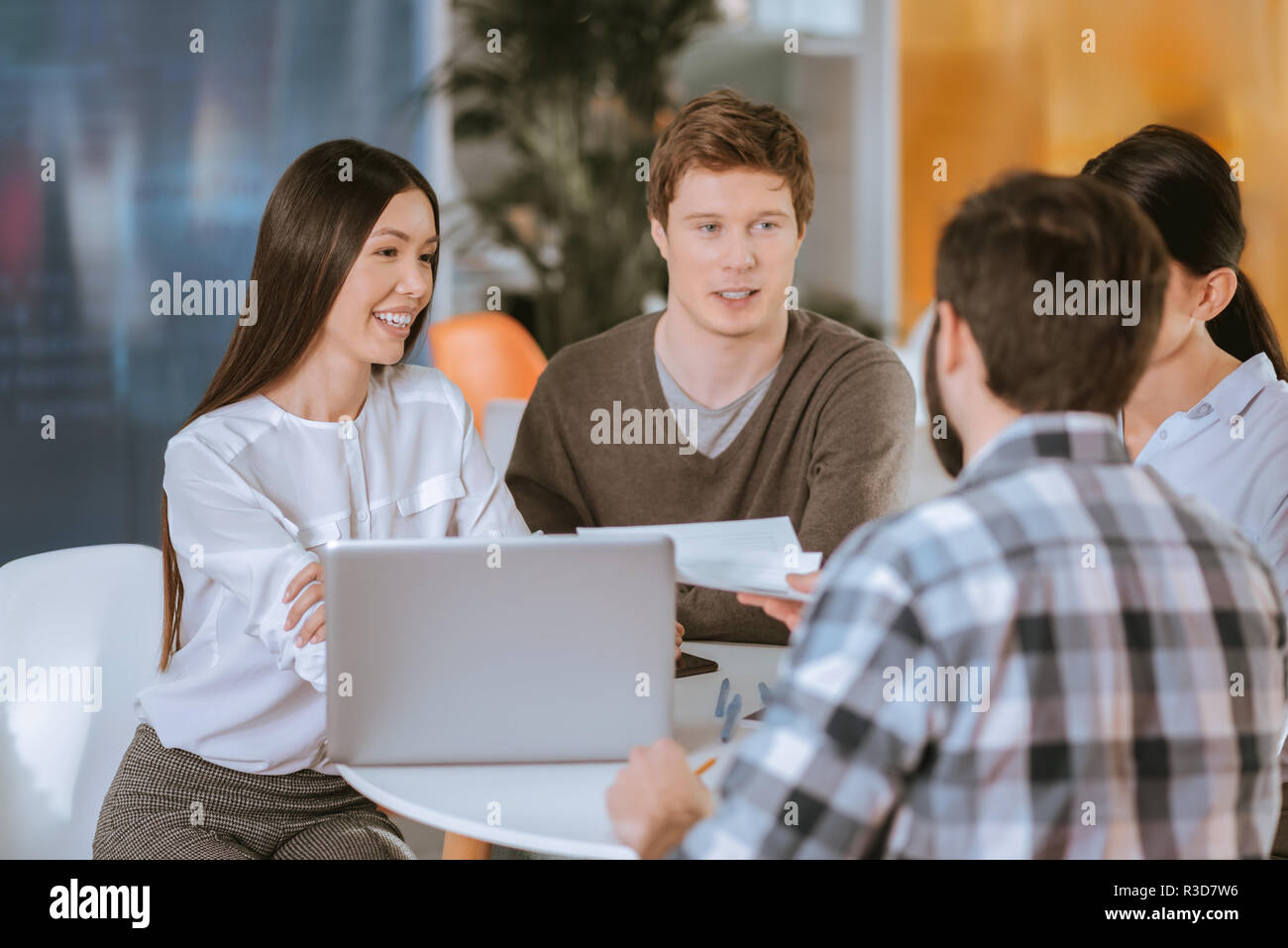 Vivid discussion. Successful four colleagues posing at table and ...