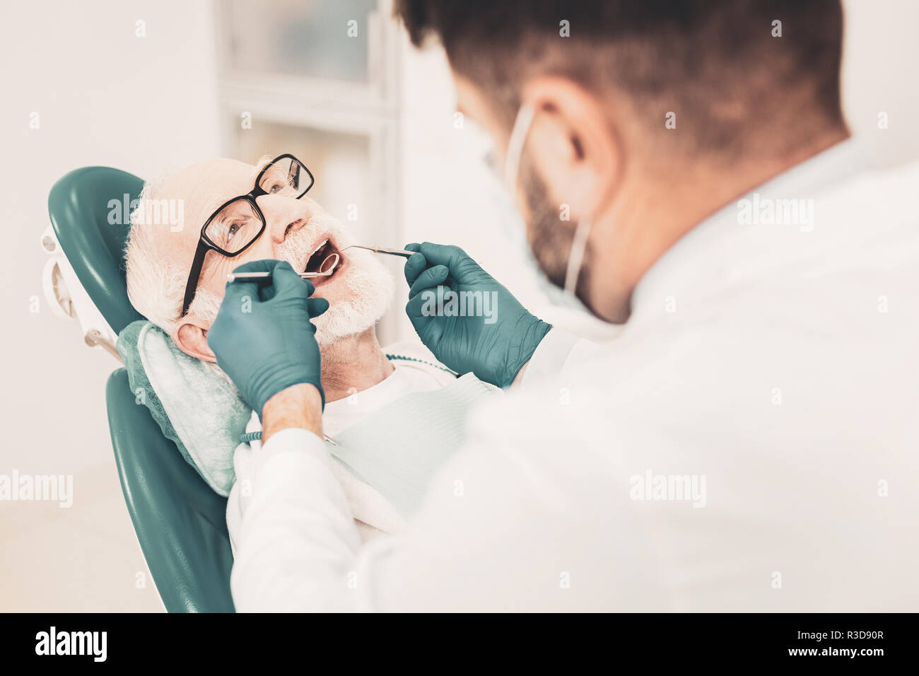 Preventative inspection. Expert doctor examining teeth of his elderly ...