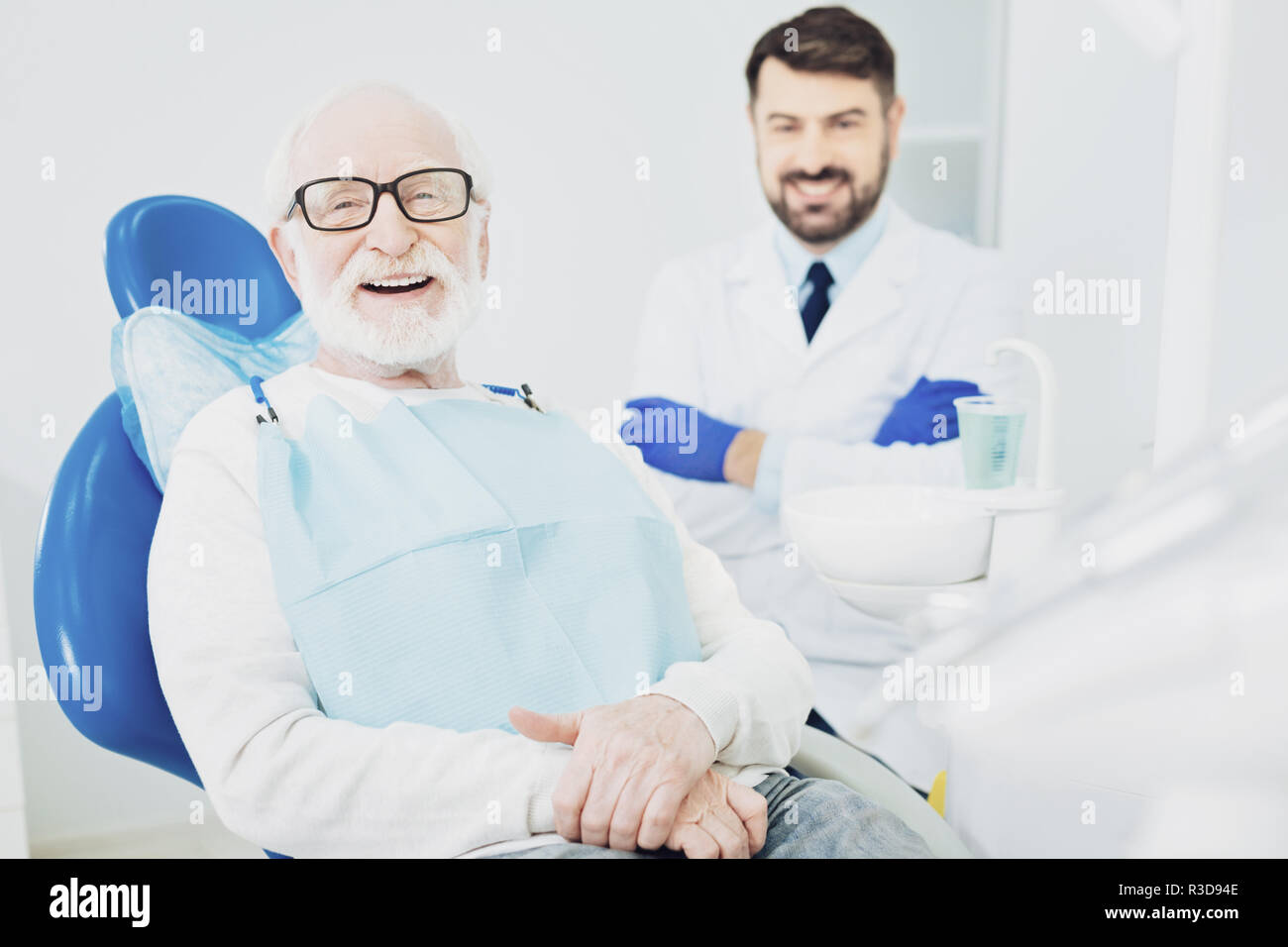 Great doctor. Cheerful senior man sitting in dentist chair while ...