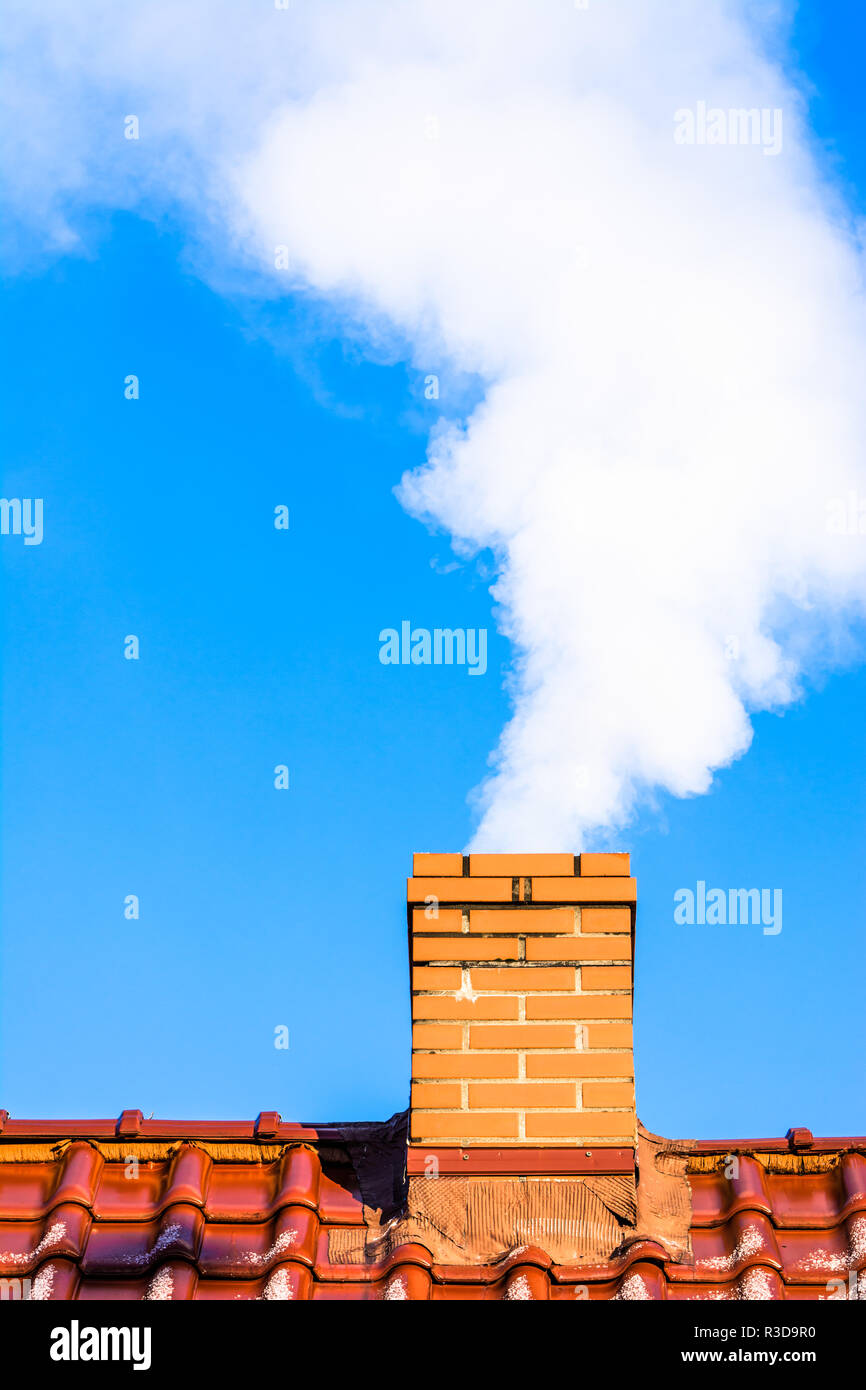 Modern house roof with chimney smoke, air pollution and smog in winter ...
