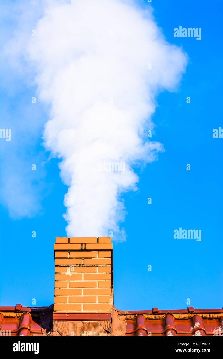 Modern house roof with chimney smoke, air pollution and smog in winter ...