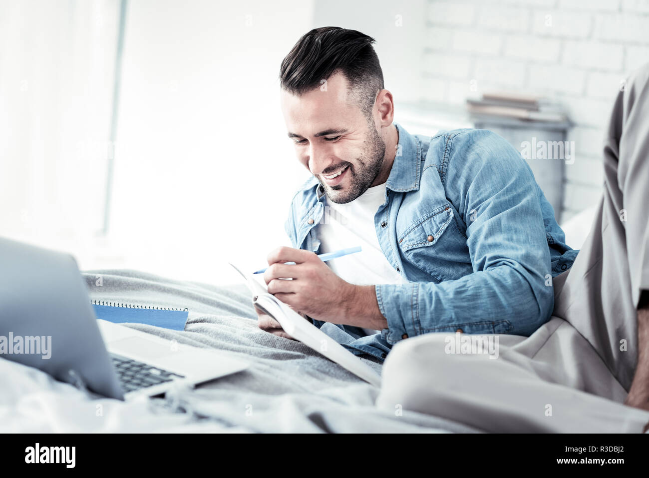 Making notes. Handsome male person keeping smile on his face and bowing ...