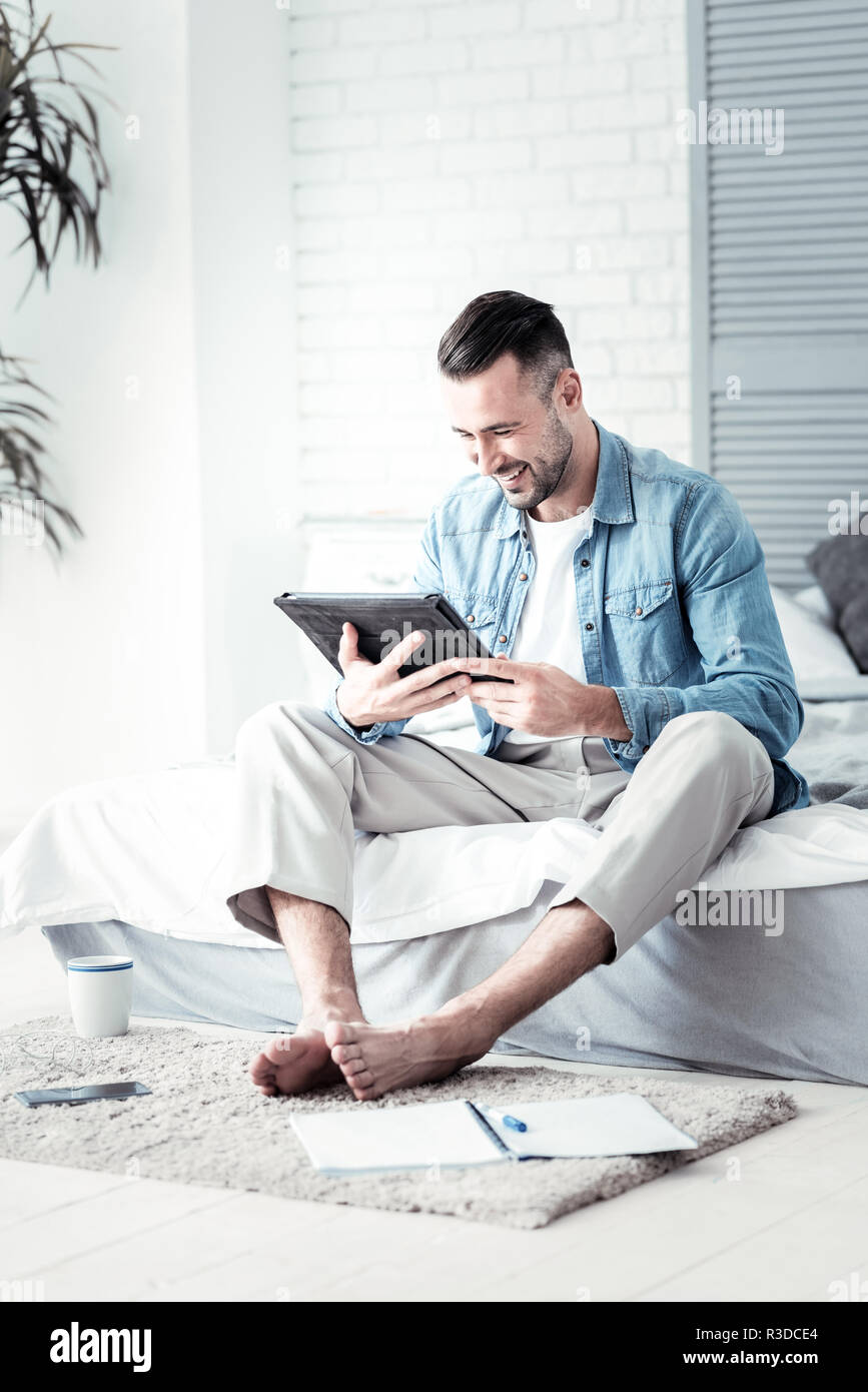 Be sociable. Handsome brunette man keeping smile on his face and ...