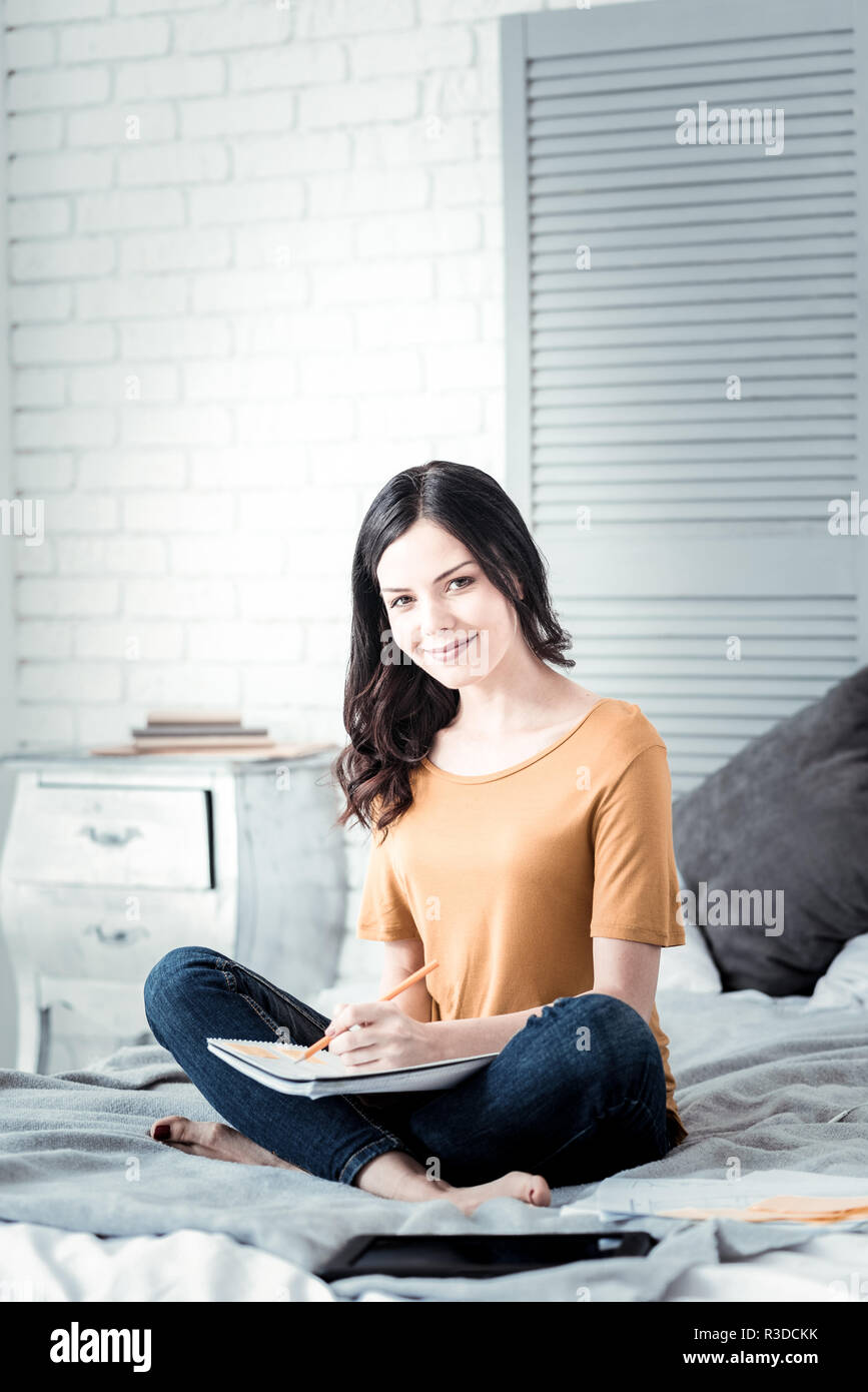 Romantic mood. Shy girl keeping smile on her face and sitting with ...