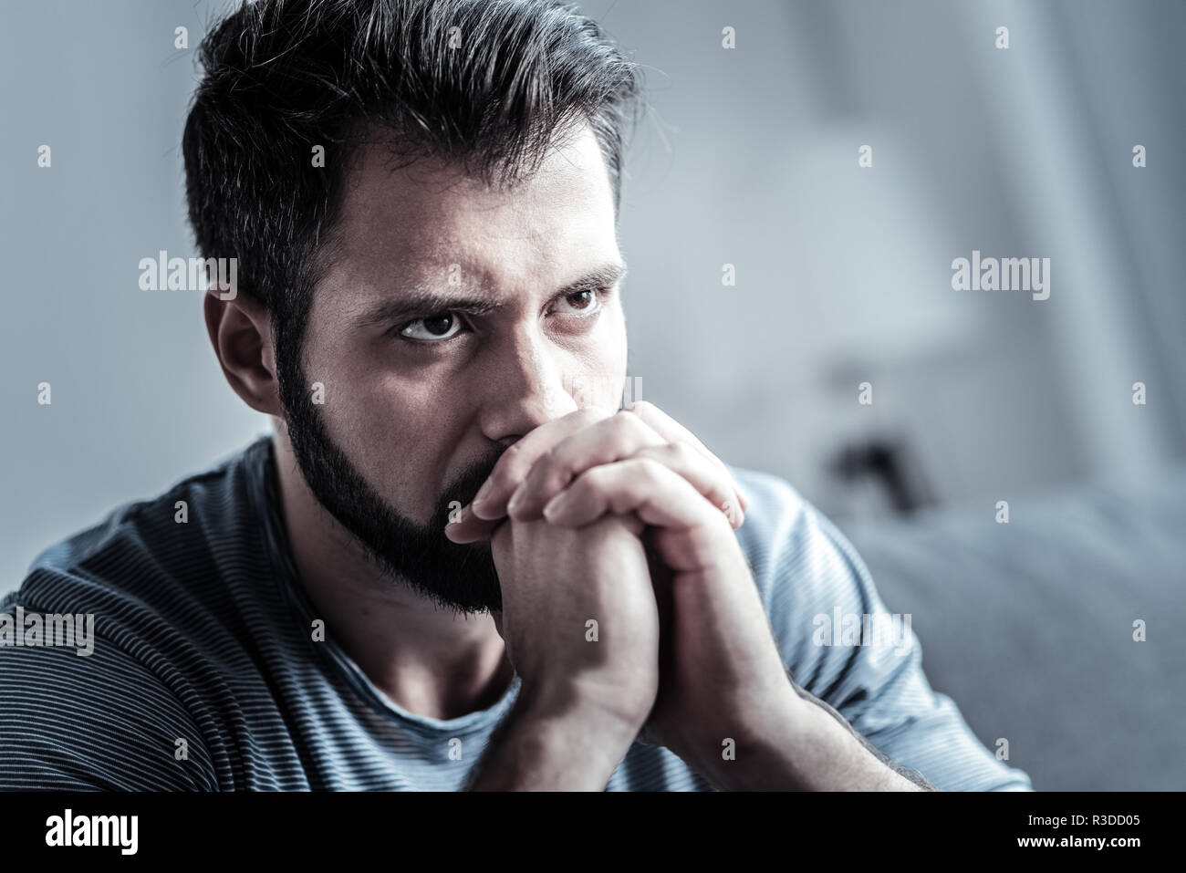 Need to think. Serious brunette sitting in his room and holding hands ...