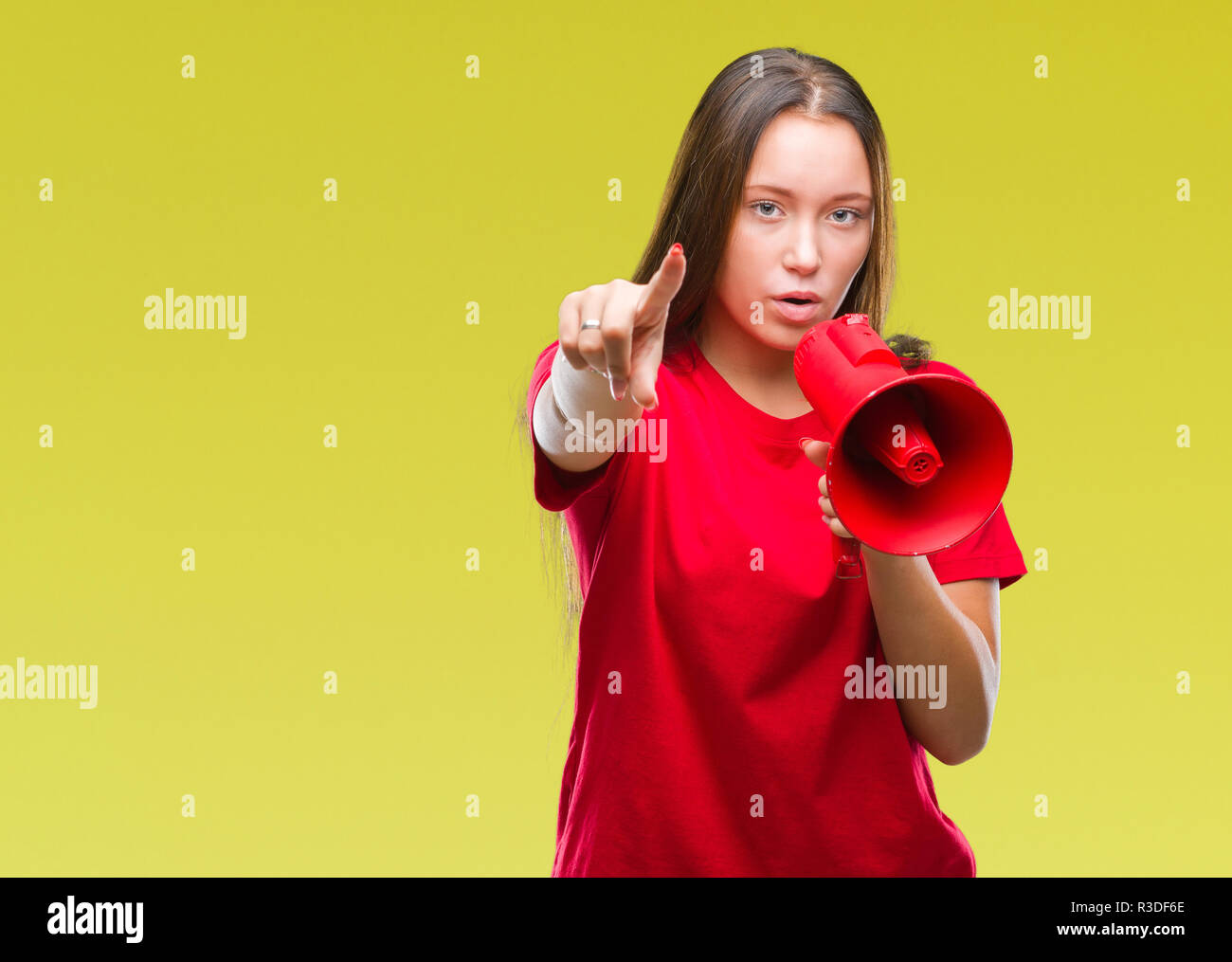 Young caucasian woman yelling through megaphone over isolated ...