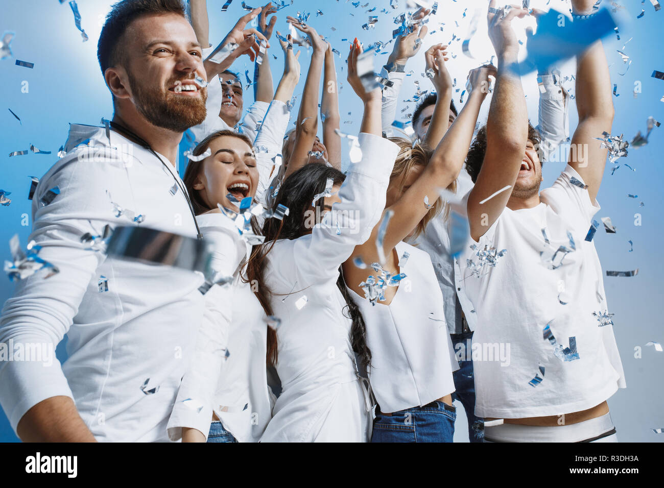 Group of cheerful joyful young people standing and celebrating together ...